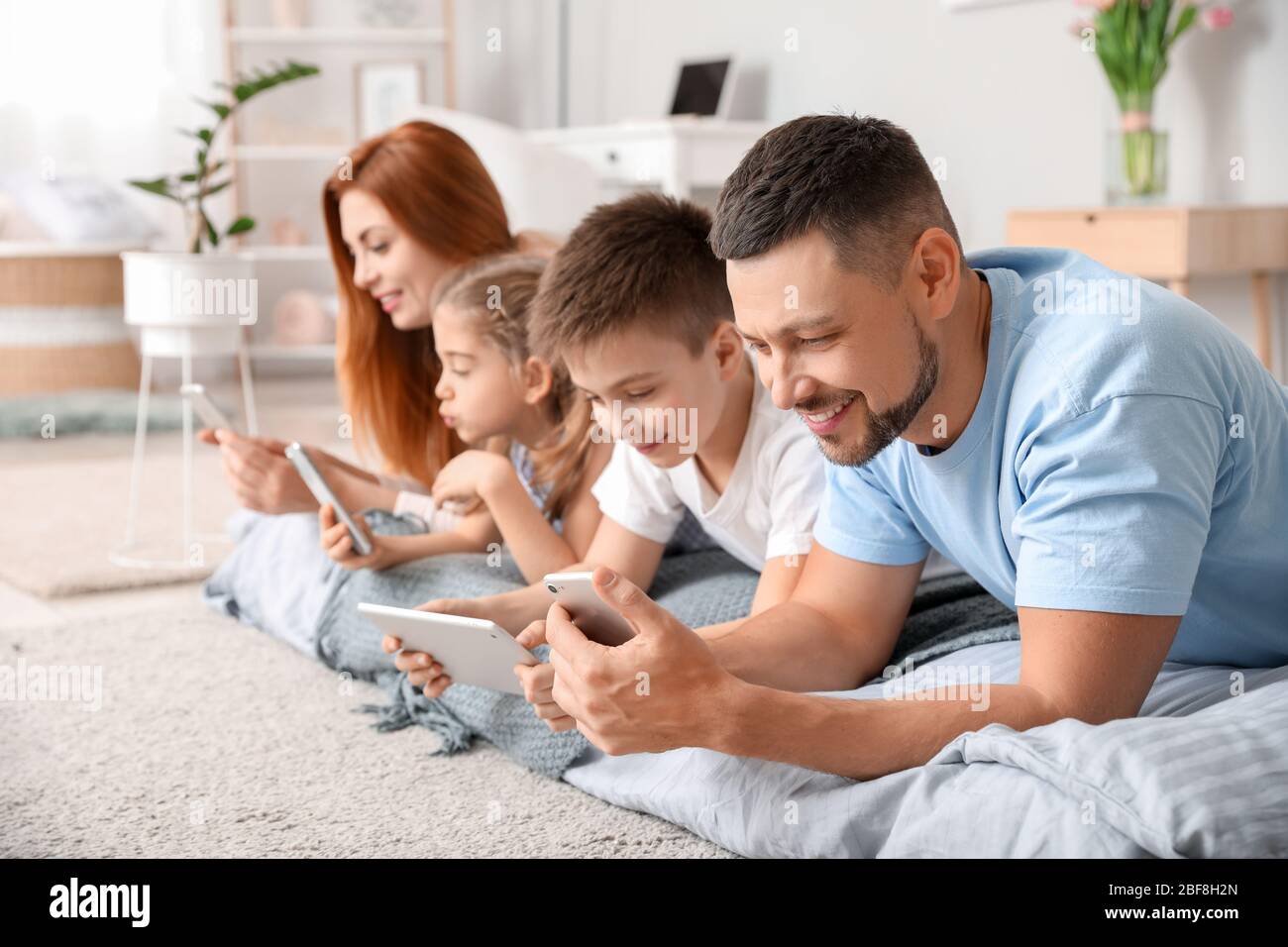 Happy family with modern devices in bedroom at home Stock Photo - Alamy