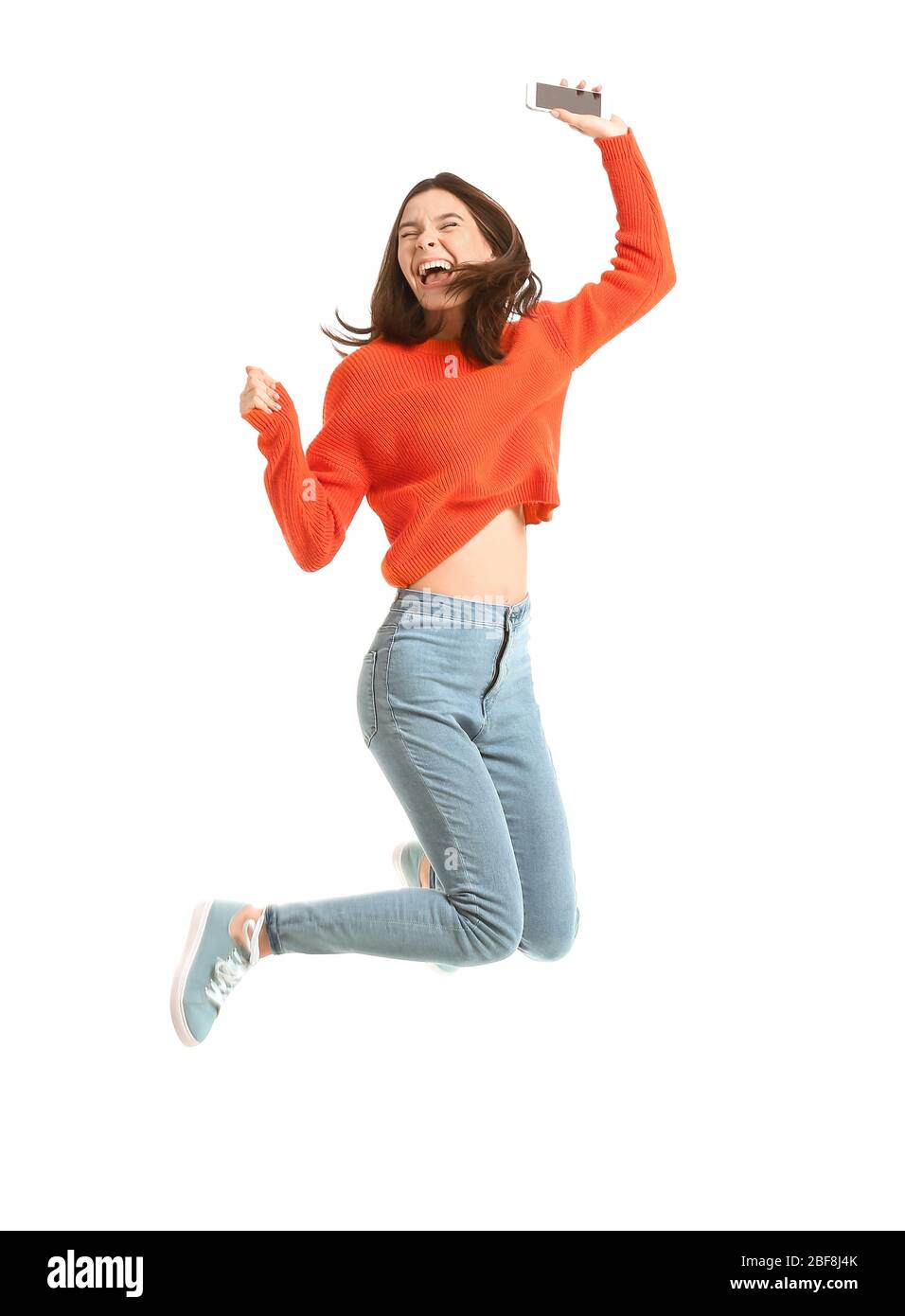 Jumping young woman with mobile phone on white background Stock Photo ...