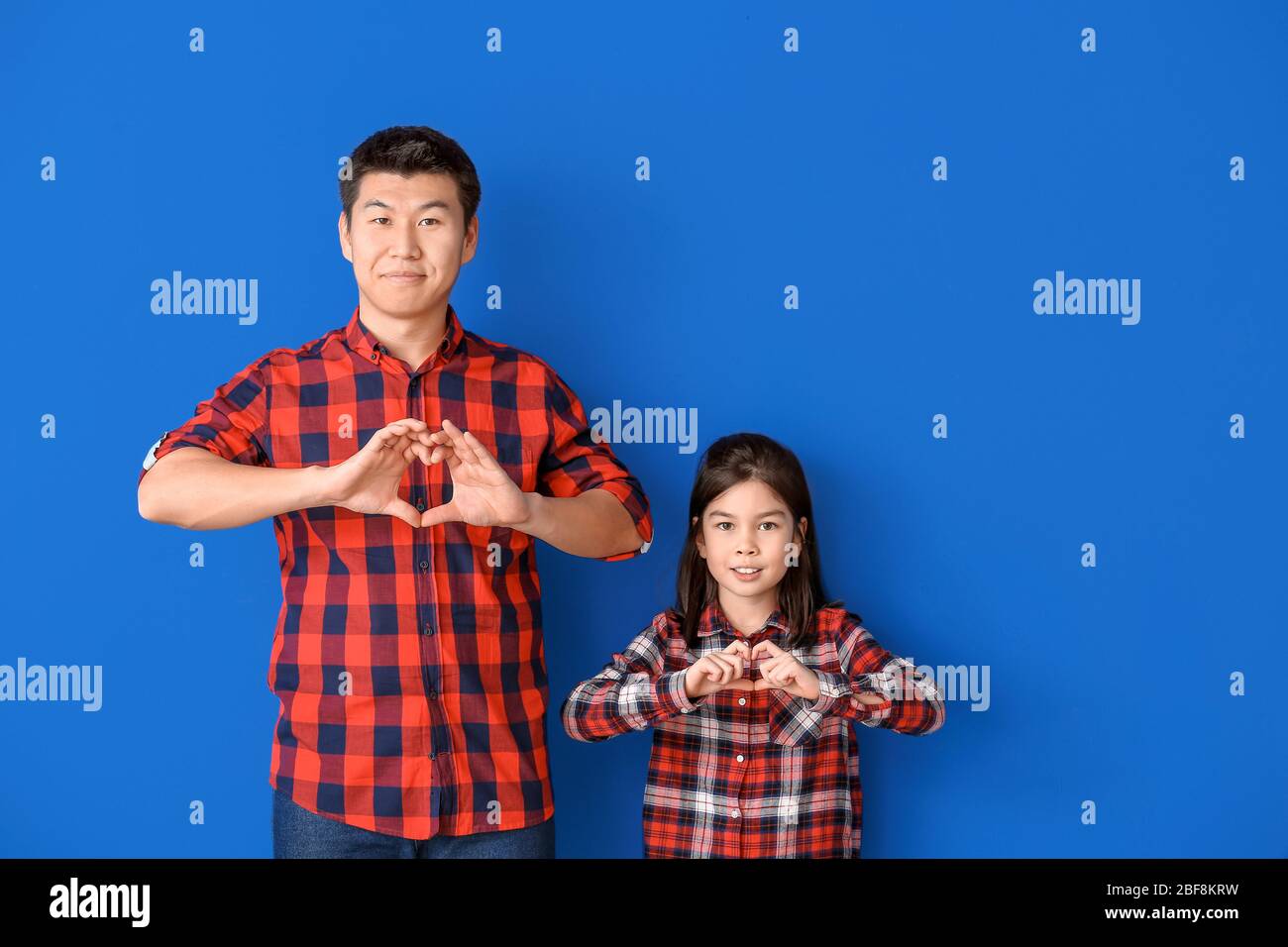 Happy Asian man and his little daughter making hearts with their hands ...