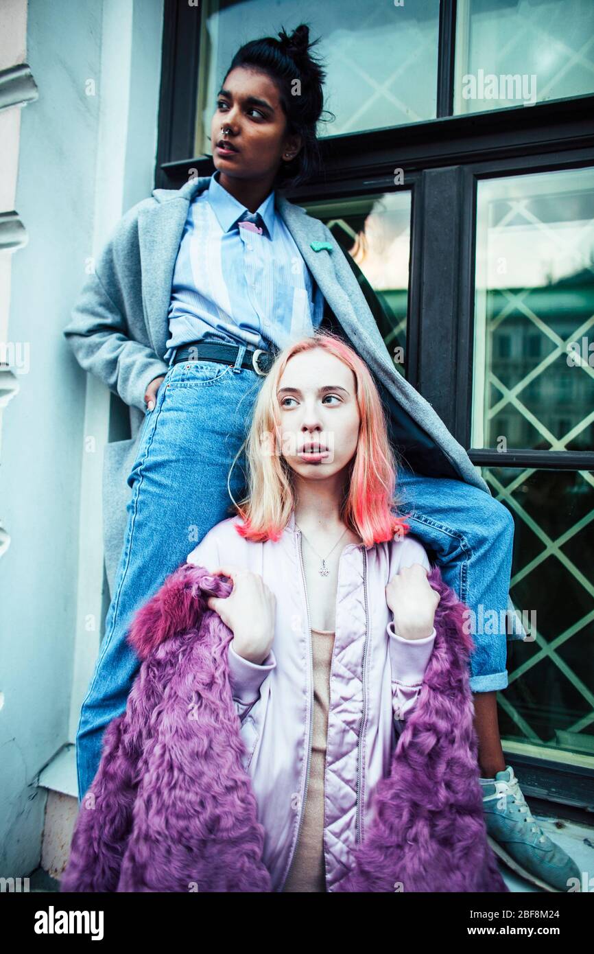 Two teenage girls infront of university building smiling, having fun ...