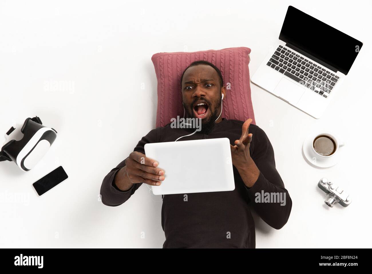 Young african-american man using devices, gadgets isolated on white ...