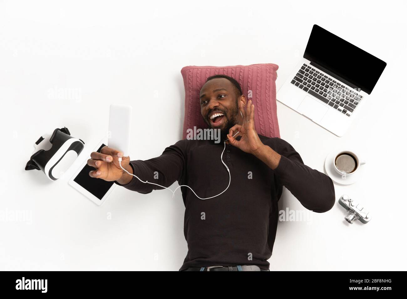 Young african-american man using devices, gadgets isolated on white ...