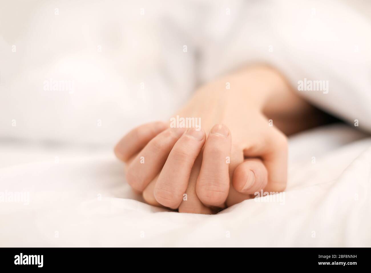 Hands of young couple sleeping in bed Stock Photo - Alamy
