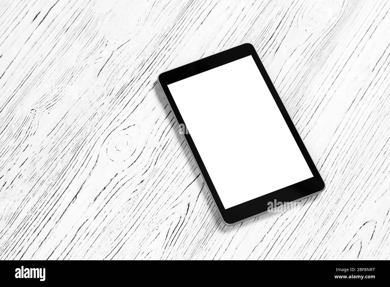 Black tablet with white screen on a wooden table. Copy space display ...