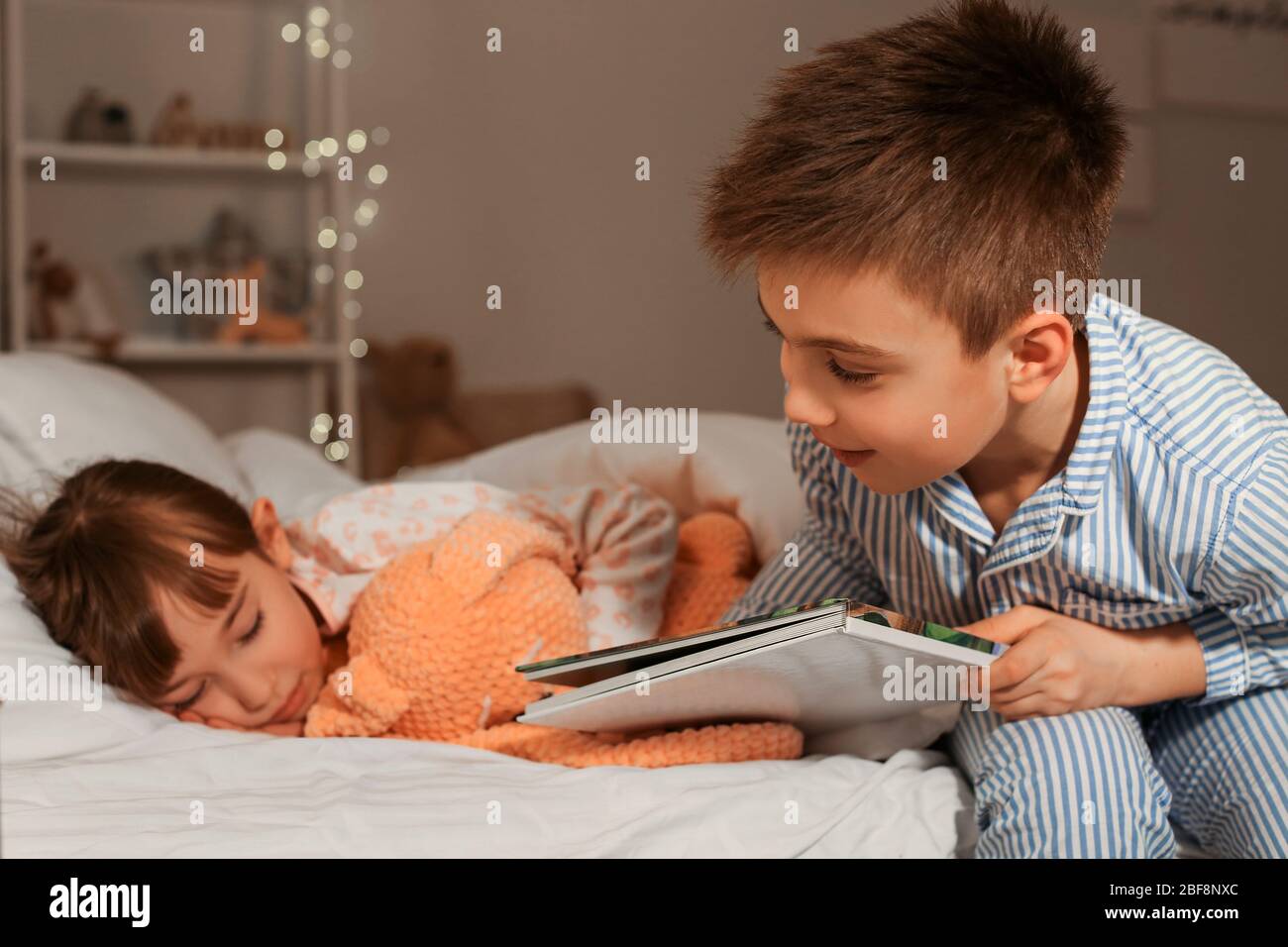 Little girl falling asleep while her brother reading bedtime story at ...