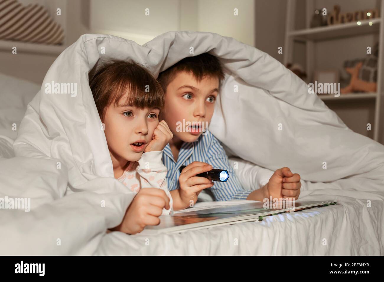 Scared little children reading bedtime story at home Stock Photo - Alamy
