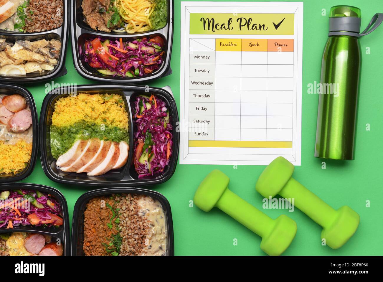 Containers with healthy food, bottle of water, dumbbells and meal plan ...