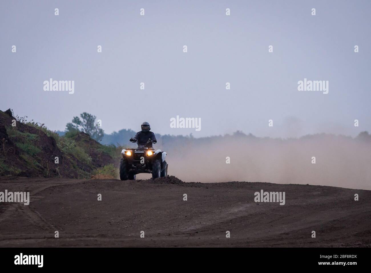 The quad racer is riding on the dirt road. Quad bike off-road. Quad ...