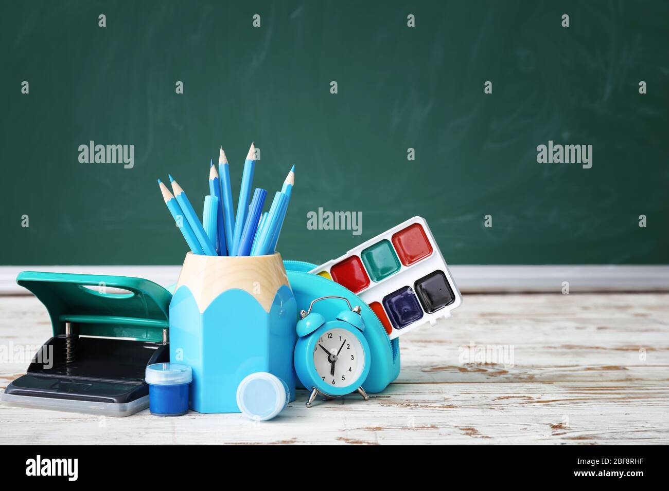 Set of school stationery and clock on table in classroom Stock Photo ...