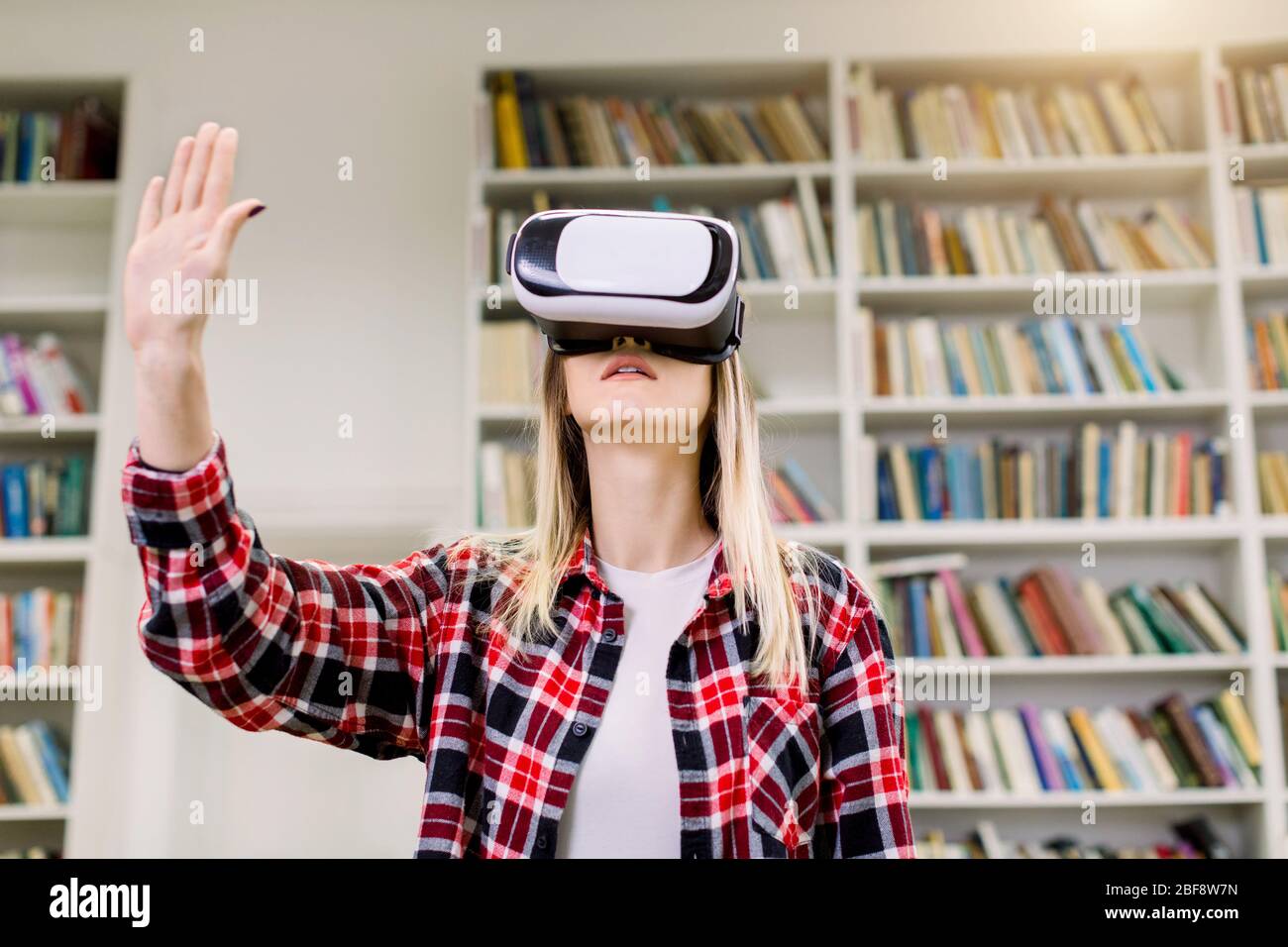 Young pretty girl, student, library user, using VR simulator while ...