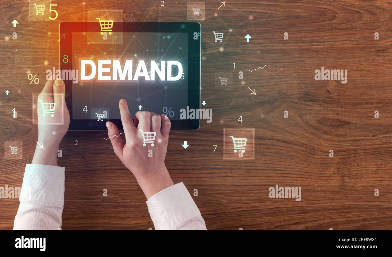 Close-up of a hand holding tablet with DEMAND inscription, online ...