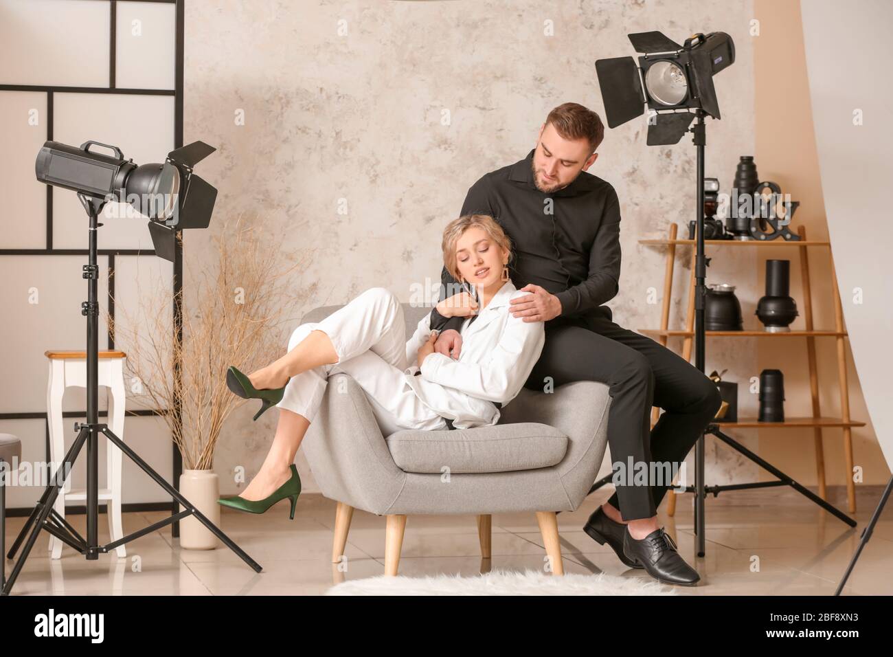 Fashionable couple posing for photographer in studio Stock Photo - Alamy