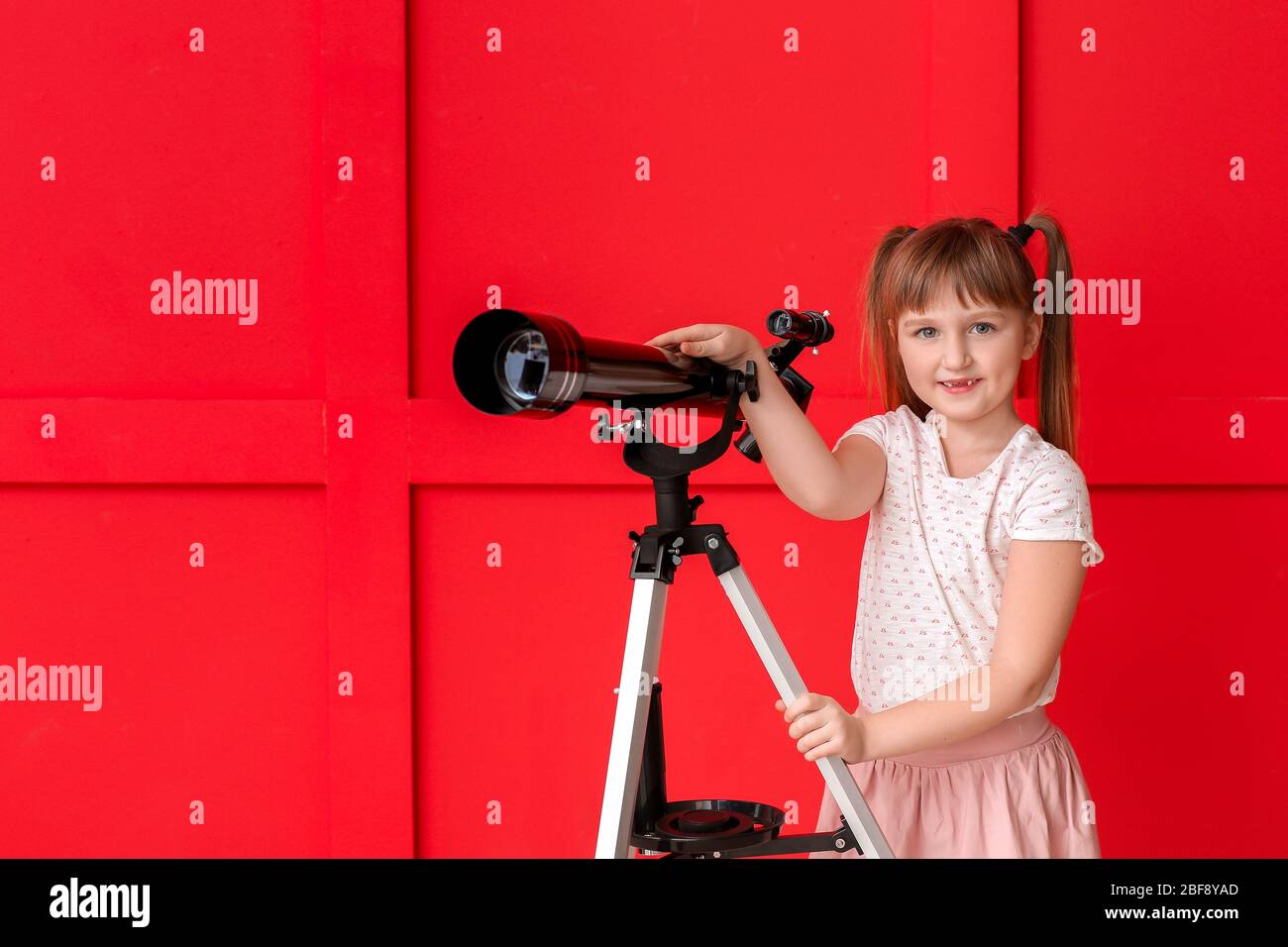 Cute little girl with telescope on color background Stock Photo - Alamy