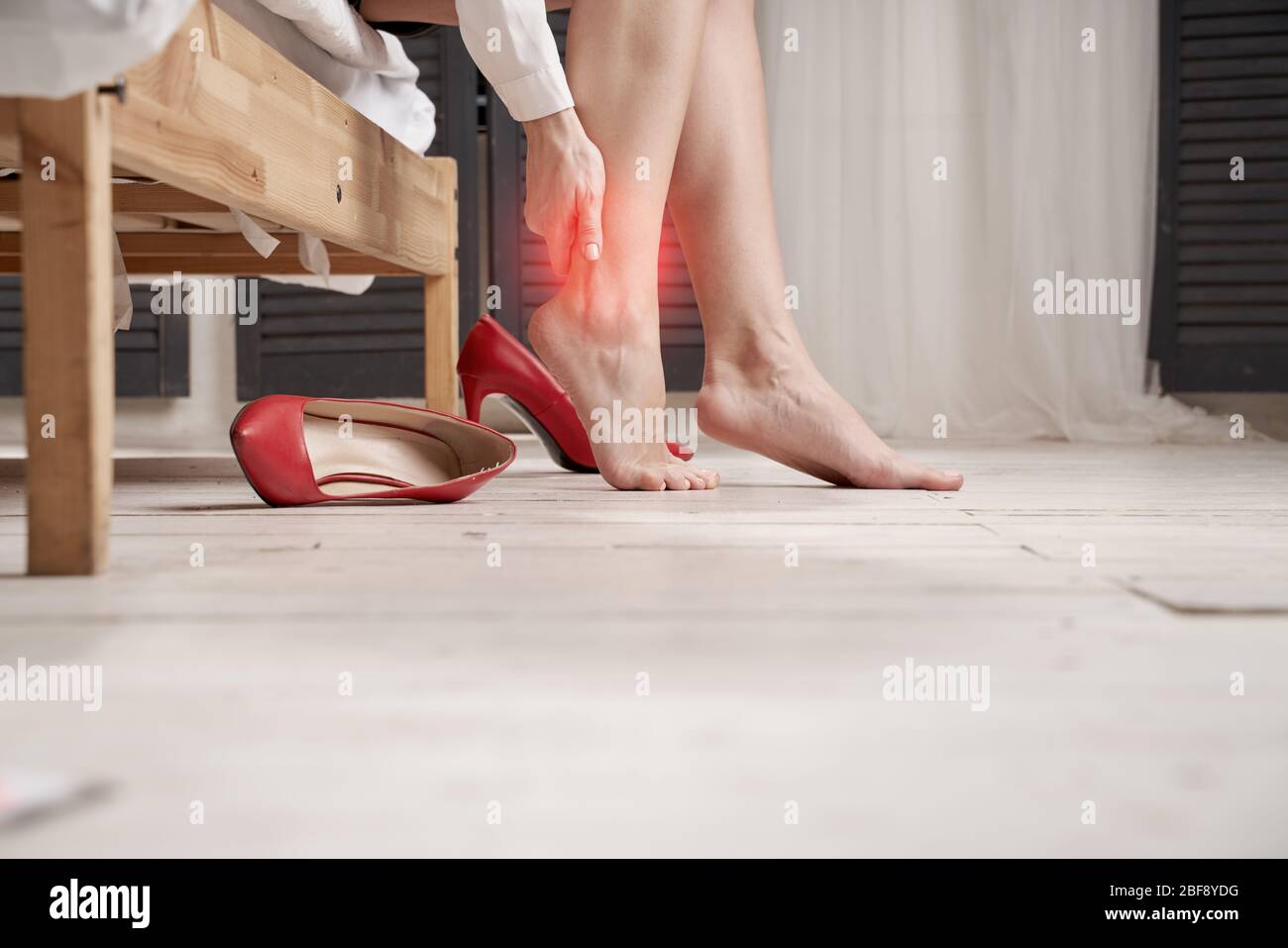 Woman is massaging sore feet in red stilettos in apartment,red spot ...