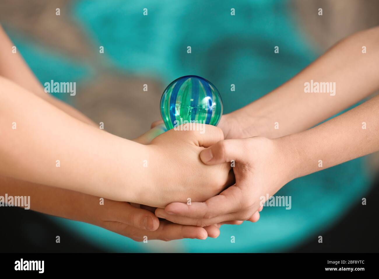Hands of little children with light bulb on blurred background. Earth ...