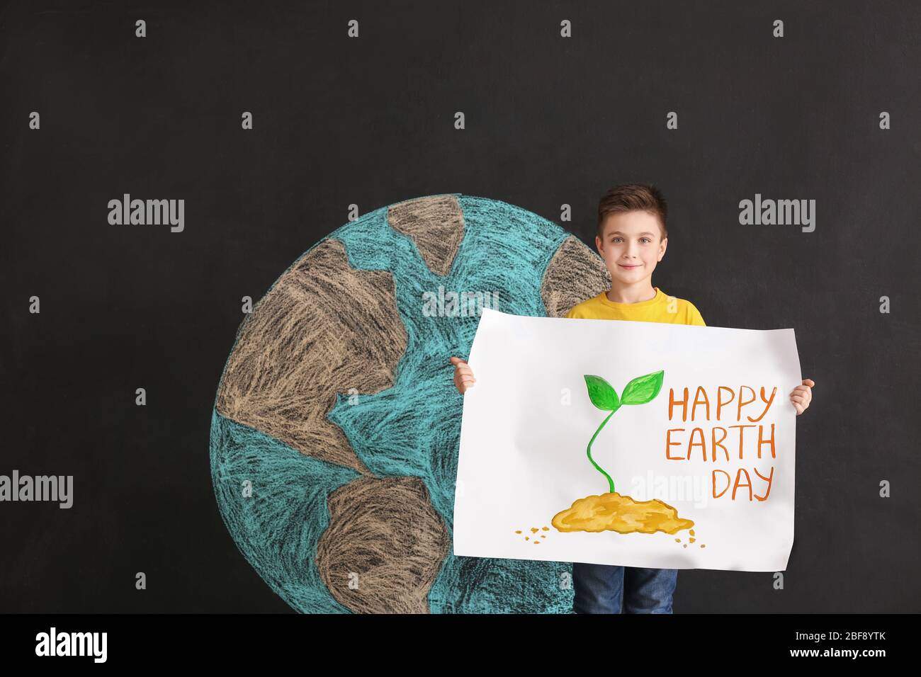Little boy with poster and drawing of planet on dark background. Earth ...