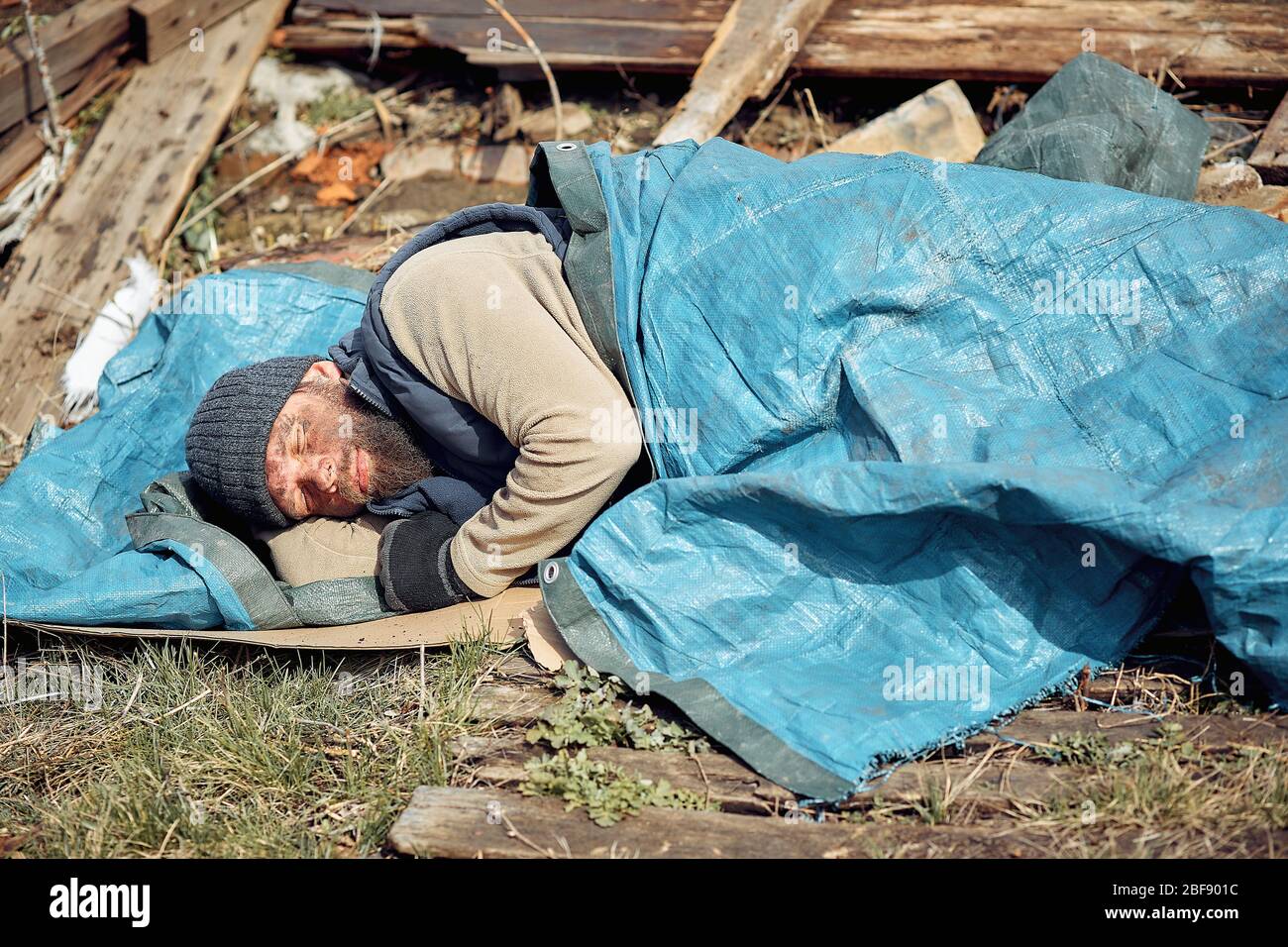 a homeless man near the ruins sleeps on cardboard boxes, helping poor ...