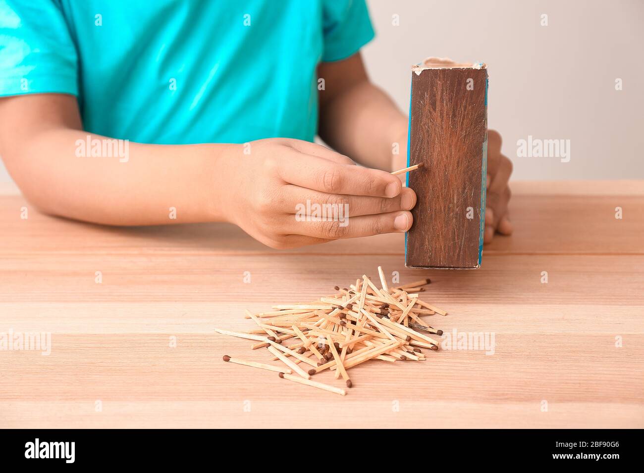 Little African-American boy with matches at table. Child in danger ...