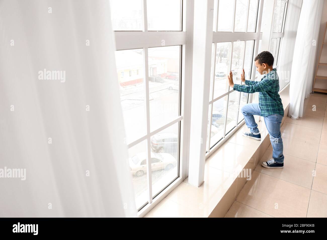 Little African-American boy near window. Child in danger Stock Photo ...