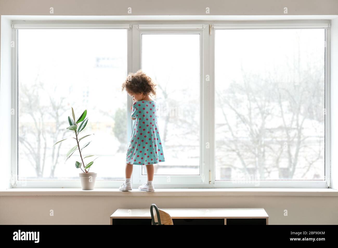 Little African-American girl near window. Child in danger Stock Photo ...