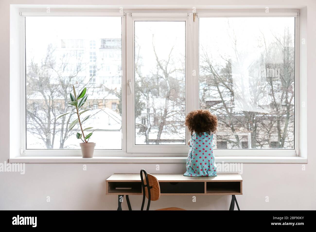 Little African-American girl near window. Child in danger Stock Photo ...