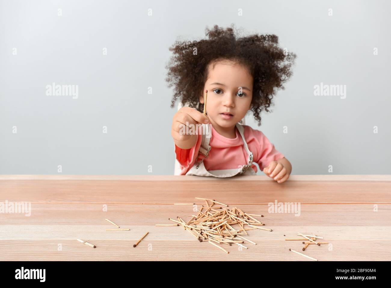 Little African-American girl playing with matches at table. Child in ...