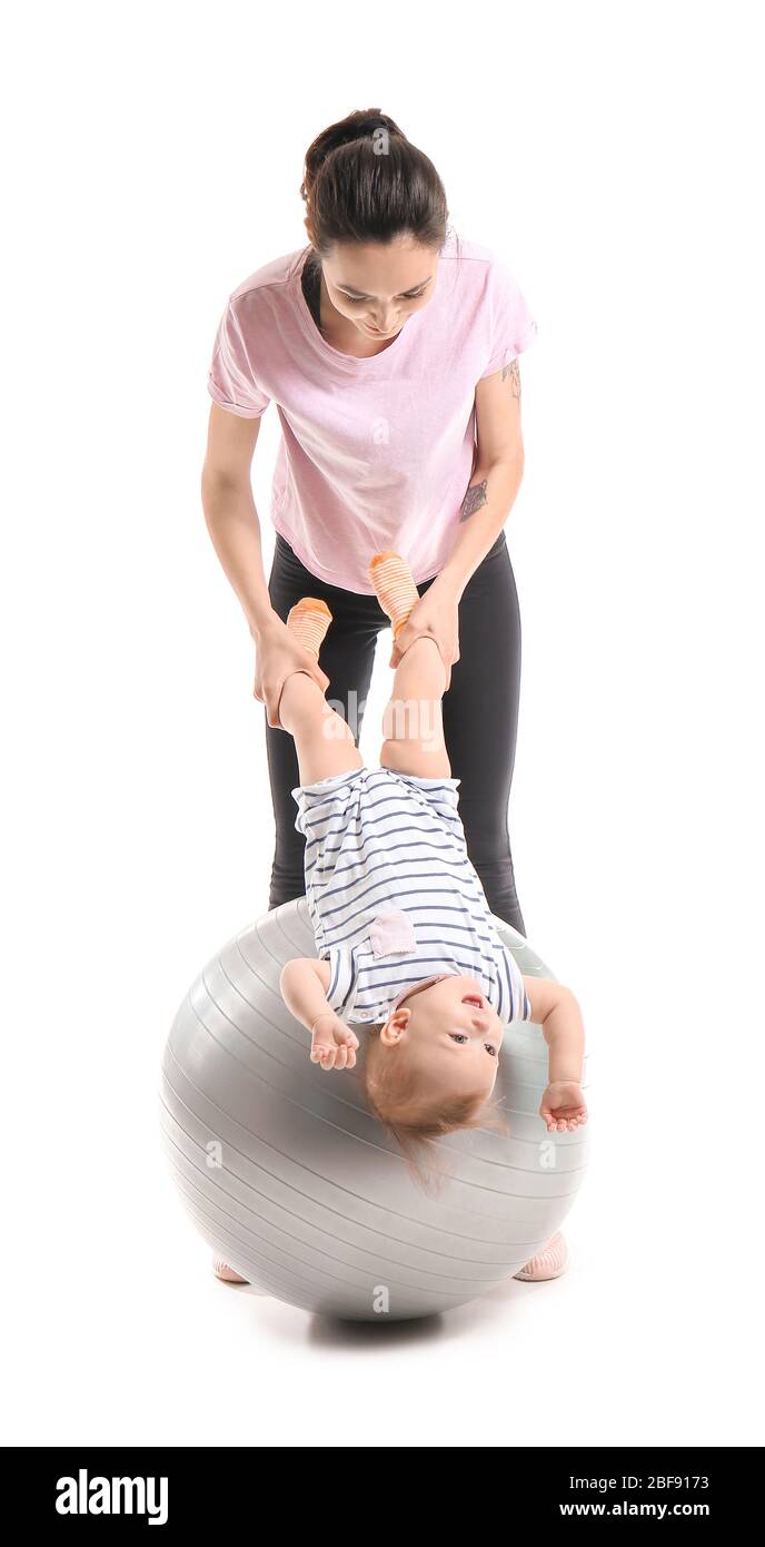 Young sporty mother and her baby doing exercises with fitball on white ...