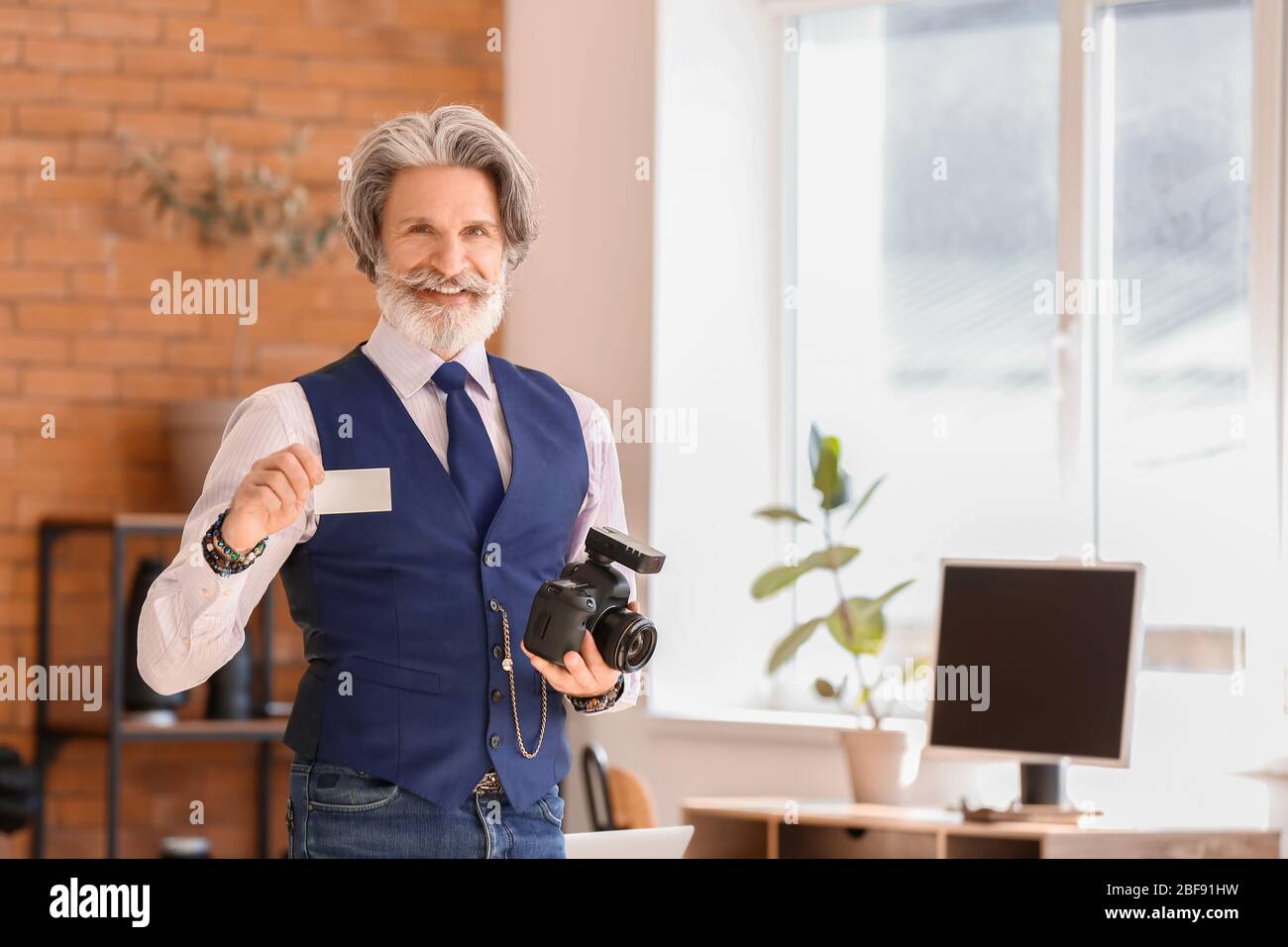 Senior photographer with business card in studio Stock Photo - Alamy