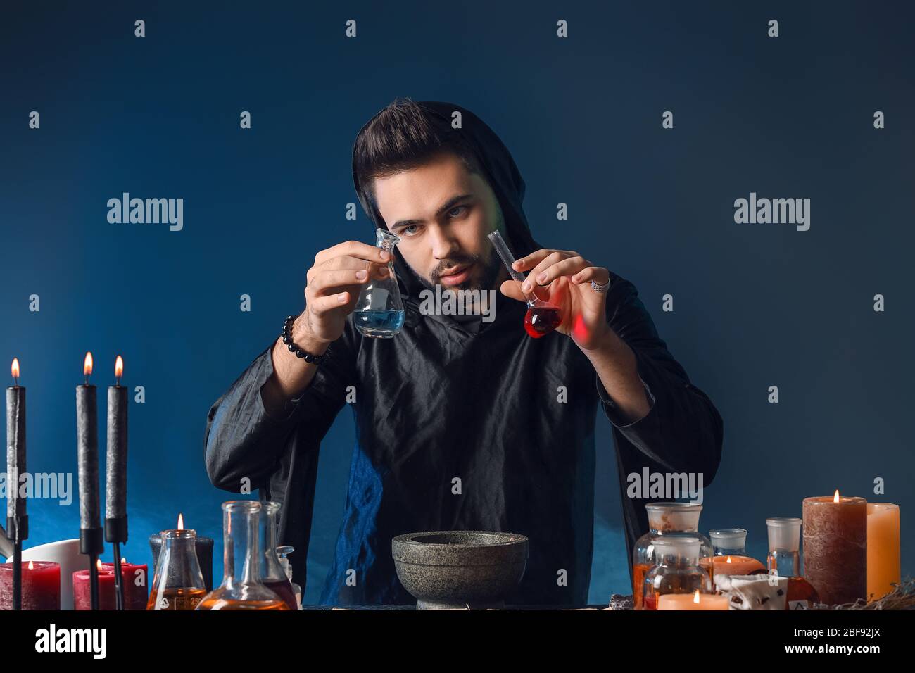 Male alchemist making potion on dark background Stock Photo - Alamy