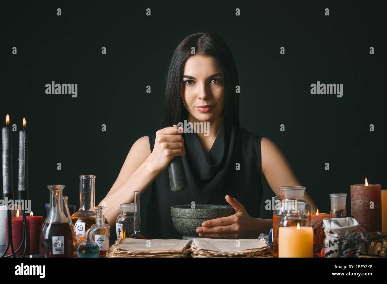 Female alchemist making potion on dark background Stock Photo - Alamy