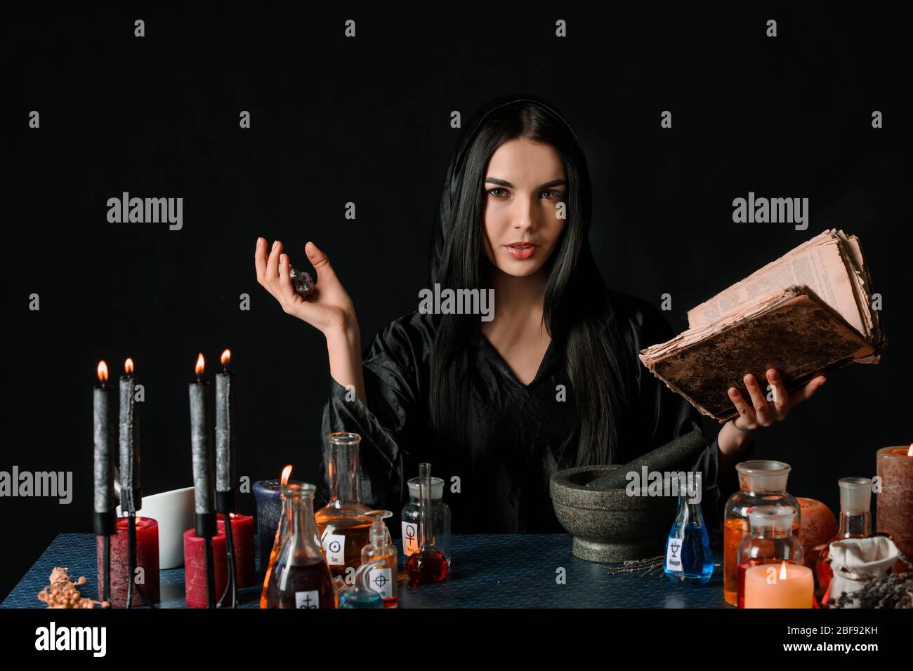 Female alchemist making potion on dark background Stock Photo - Alamy