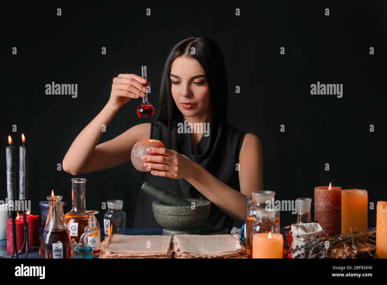 Female alchemist making potion on dark background Stock Photo - Alamy
