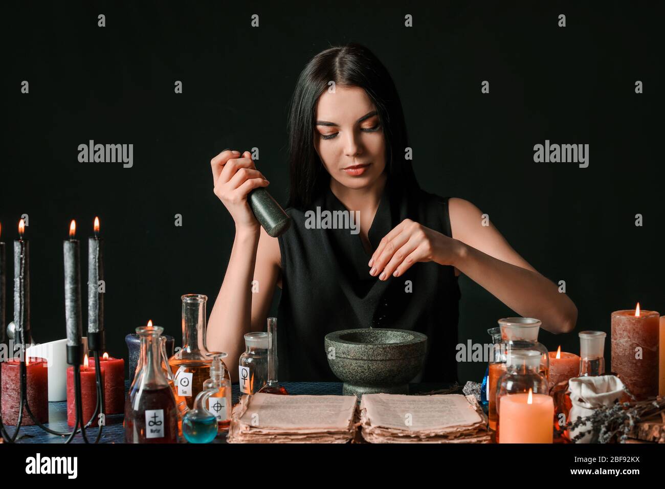 Female alchemist making potion on dark background Stock Photo - Alamy