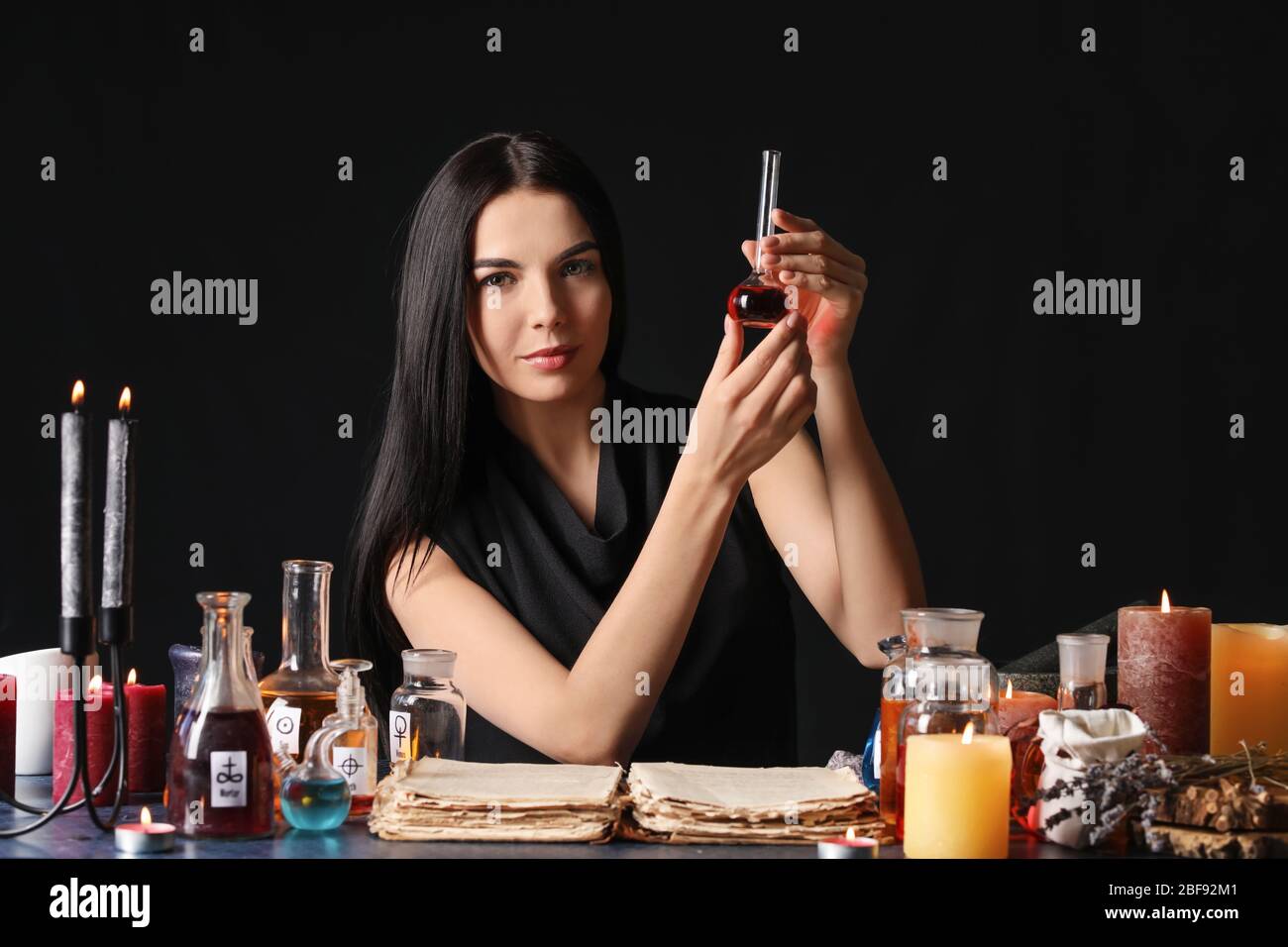 Female alchemist making potion on dark background Stock Photo - Alamy