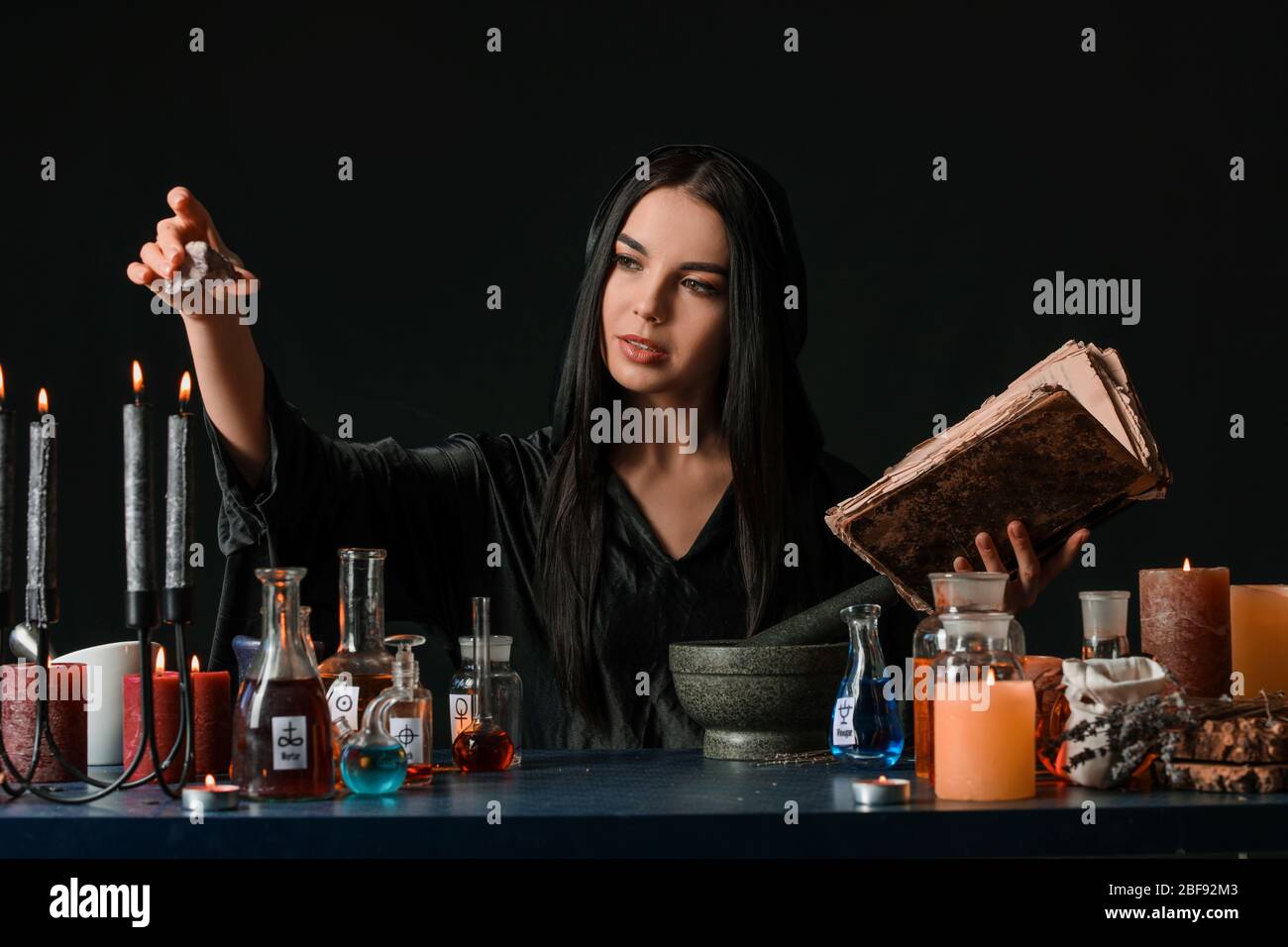 Female alchemist making potion on dark background Stock Photo - Alamy