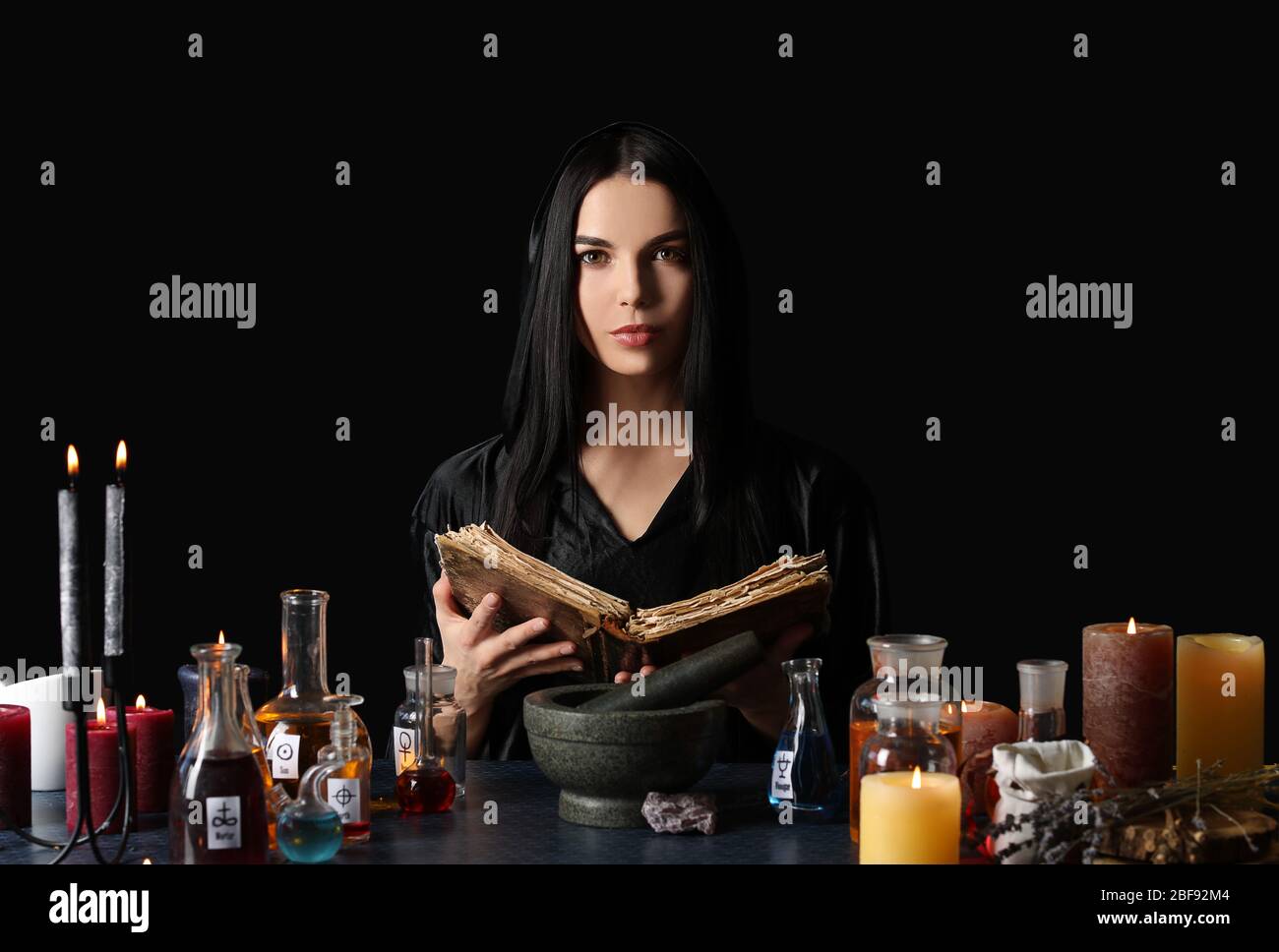 Female alchemist making potion on dark background Stock Photo - Alamy