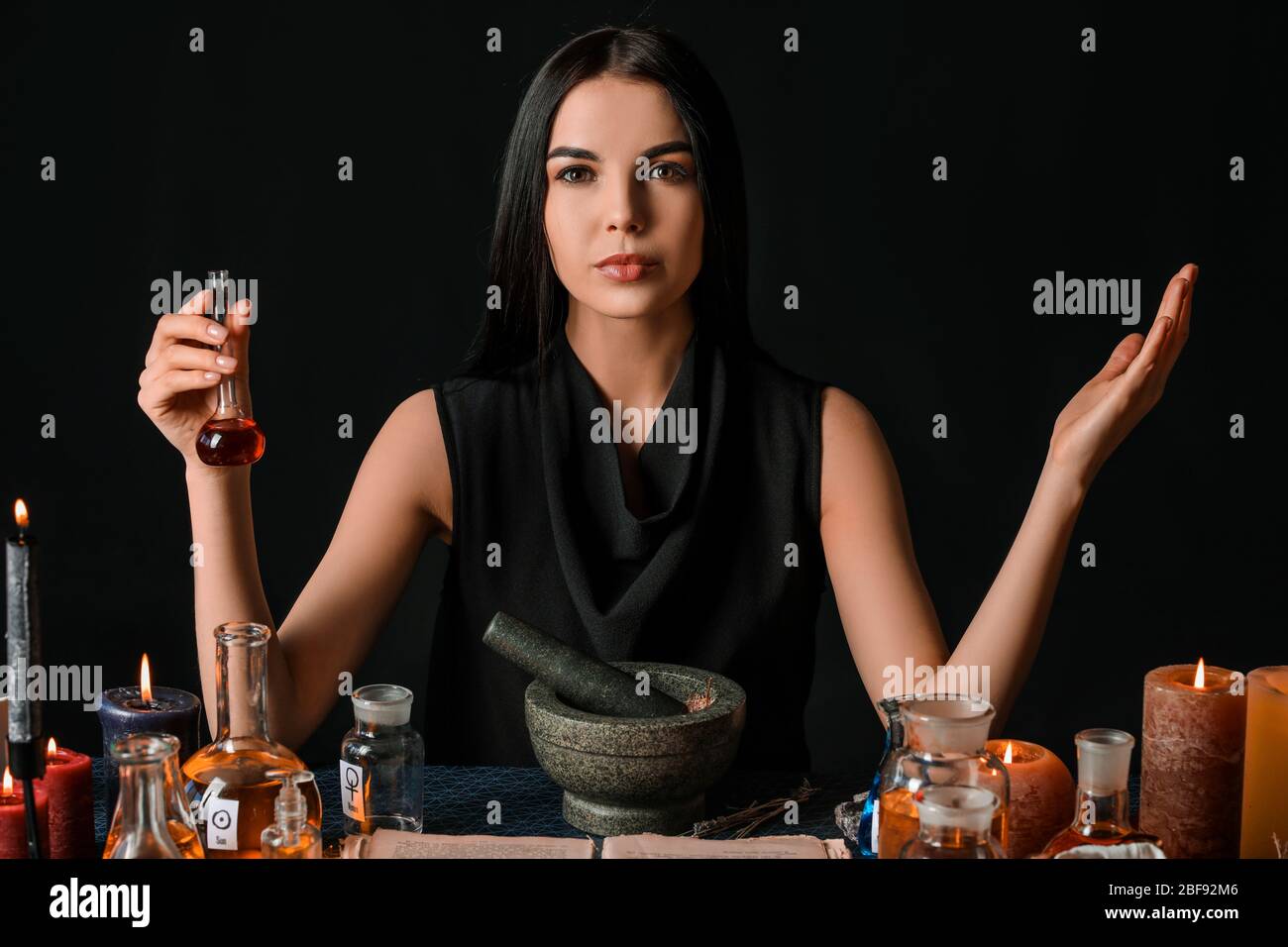 Female alchemist making potion on dark background Stock Photo - Alamy