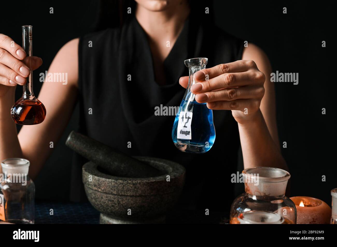 Female alchemist making potion on dark background Stock Photo - Alamy