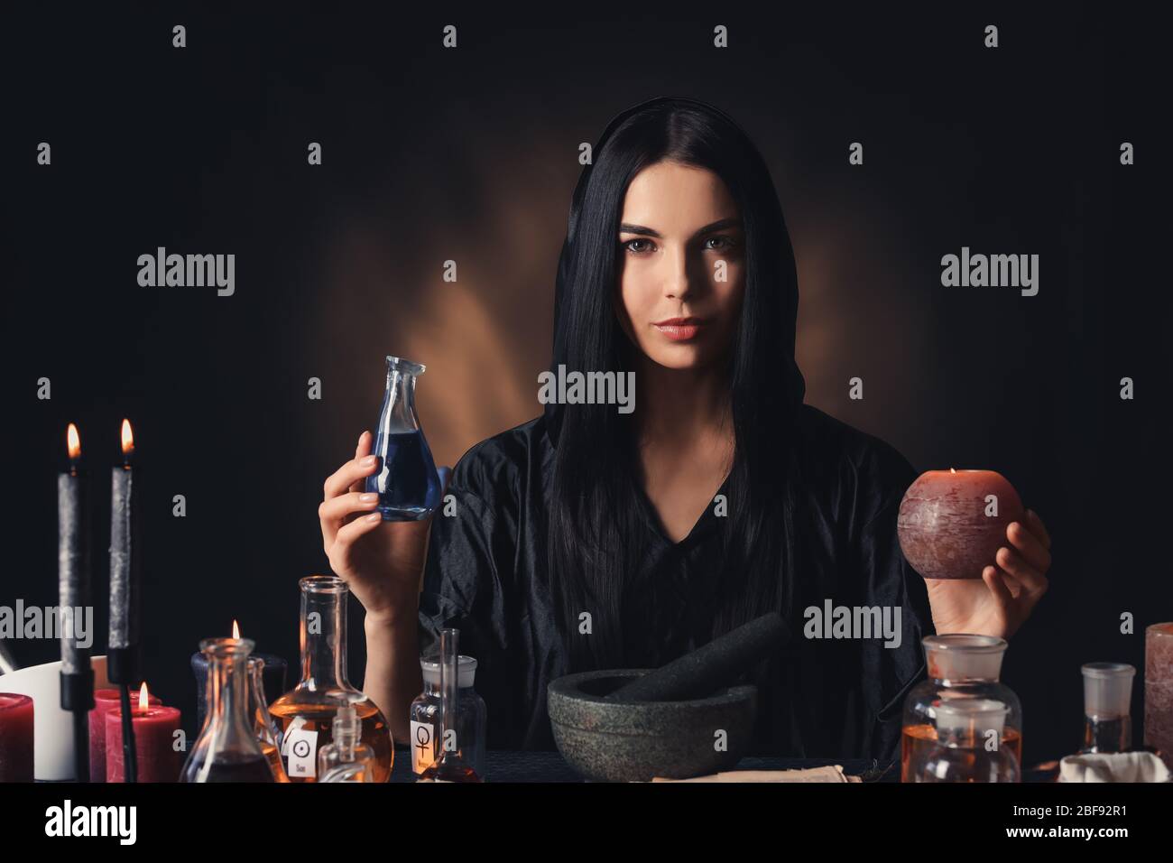 Female alchemist making potion on dark background Stock Photo - Alamy
