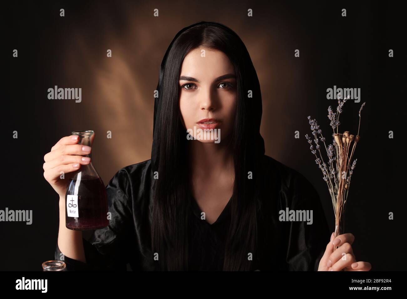 Female alchemist with potion on dark background Stock Photo - Alamy