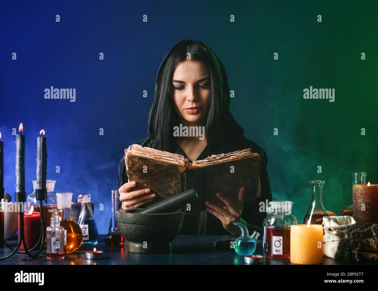 Female alchemist making potion on dark background Stock Photo - Alamy