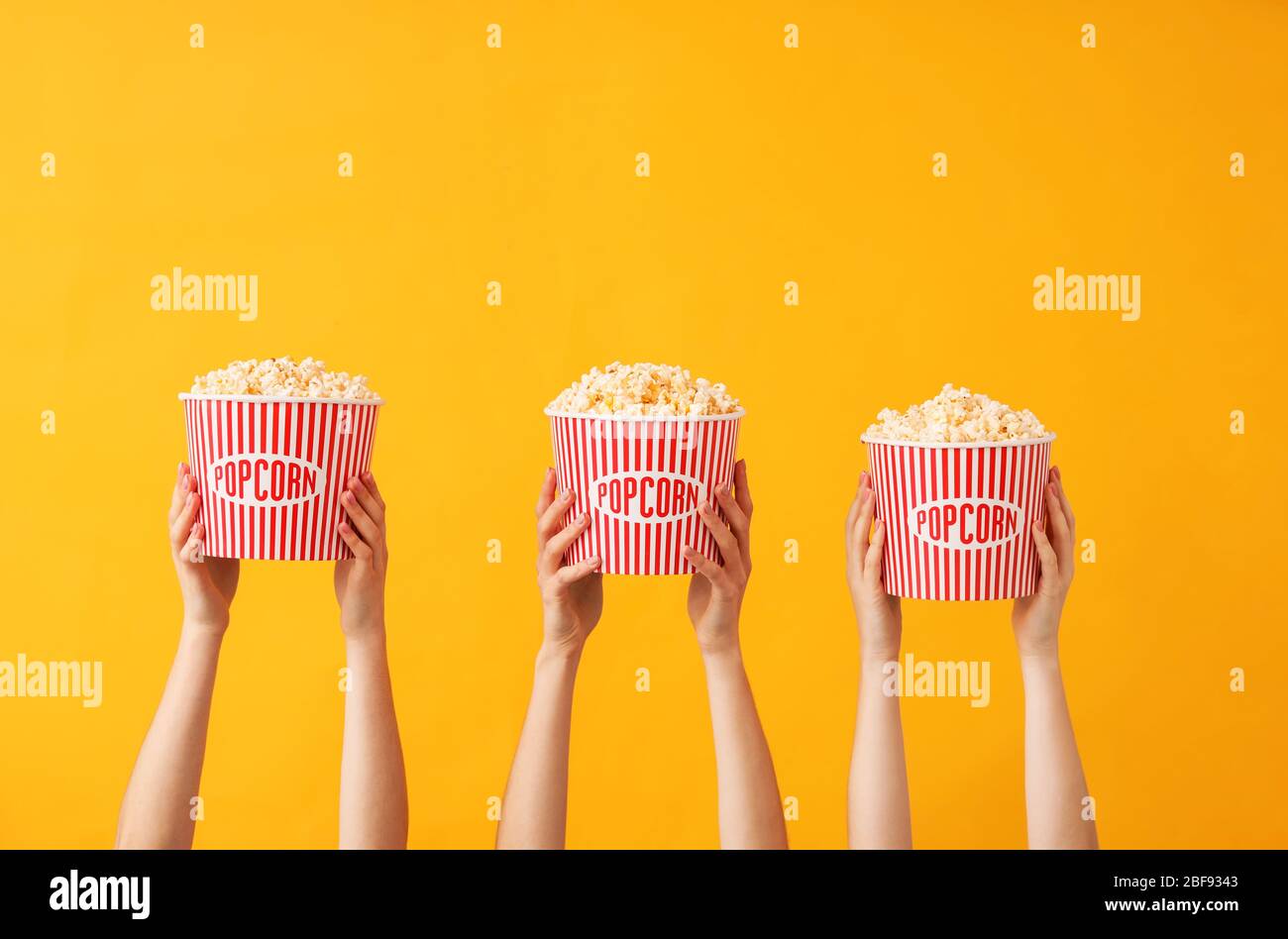 Many hands with popcorn in buckets on color background Stock Photo - Alamy