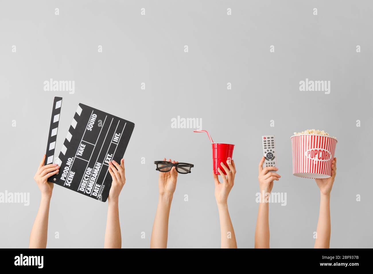 Many hands with popcorn, drink, remote control, movie clapper and ...