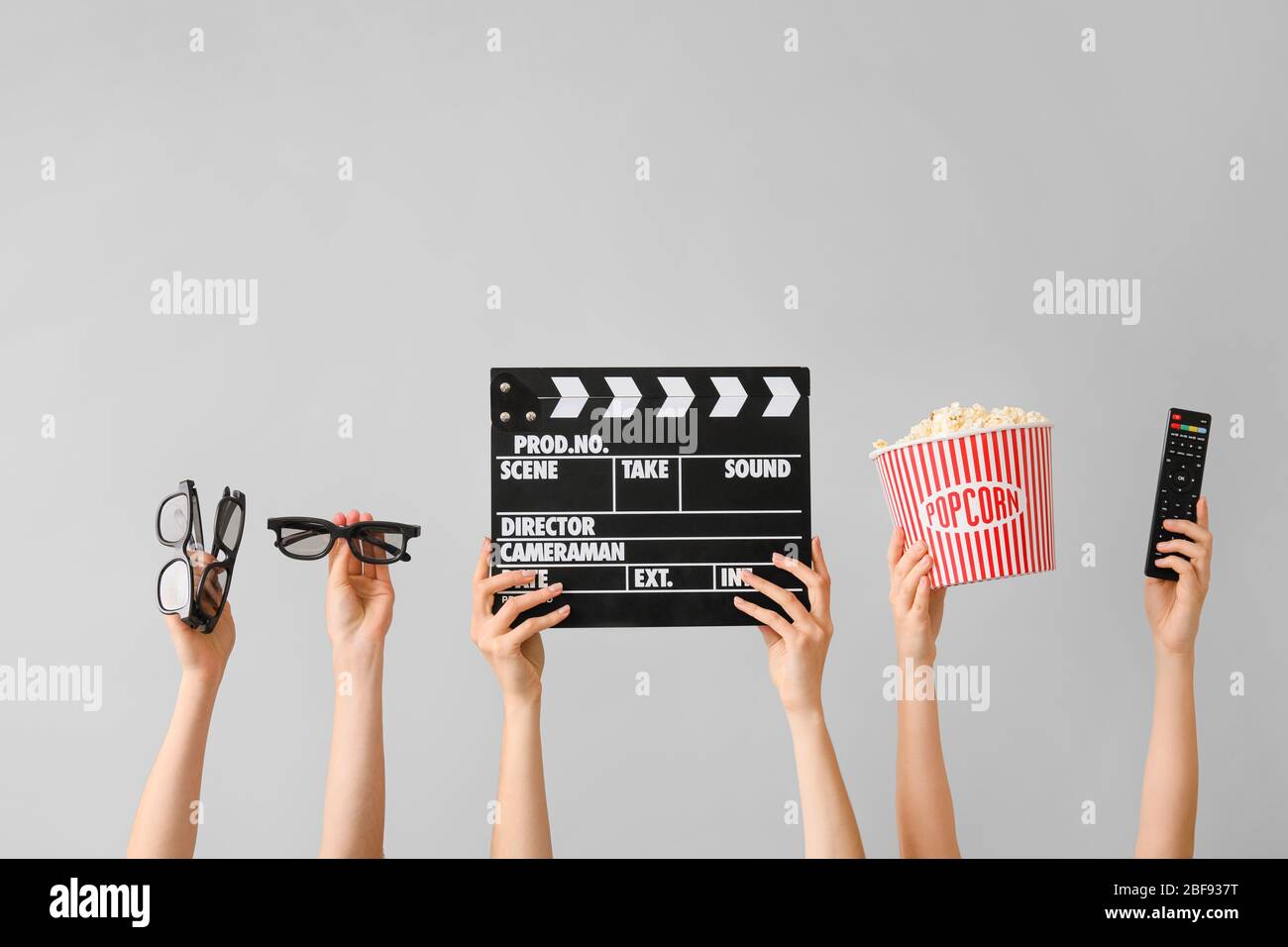 Many hands with popcorn, remote control, movie clapper and eyeglasses ...