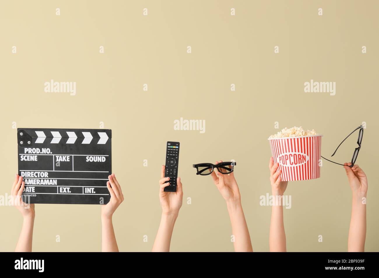 Many hands with popcorn, remote control, movie clapper and eyeglasses ...