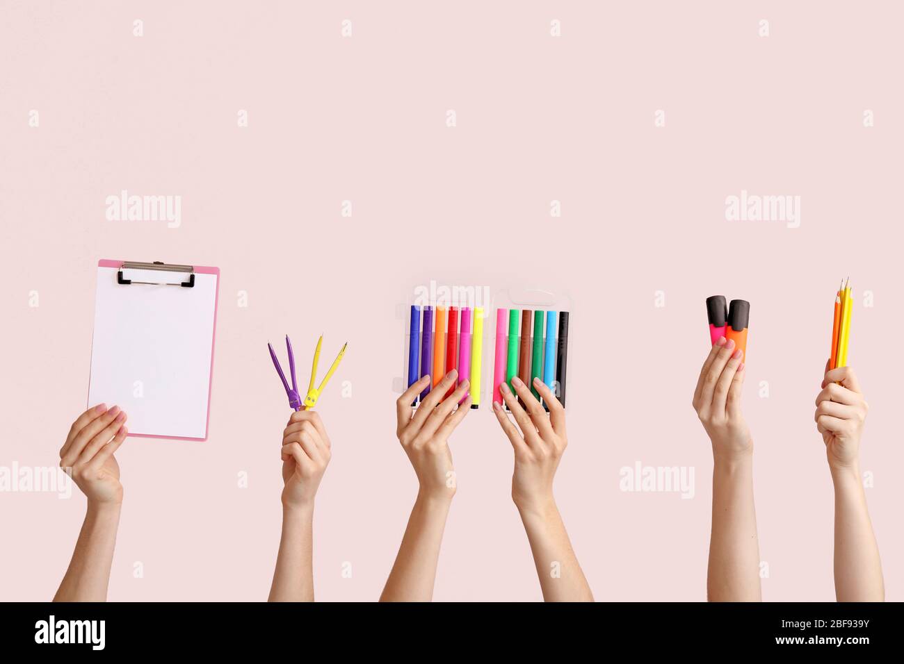 Many hands with school supplies on light background Stock Photo - Alamy