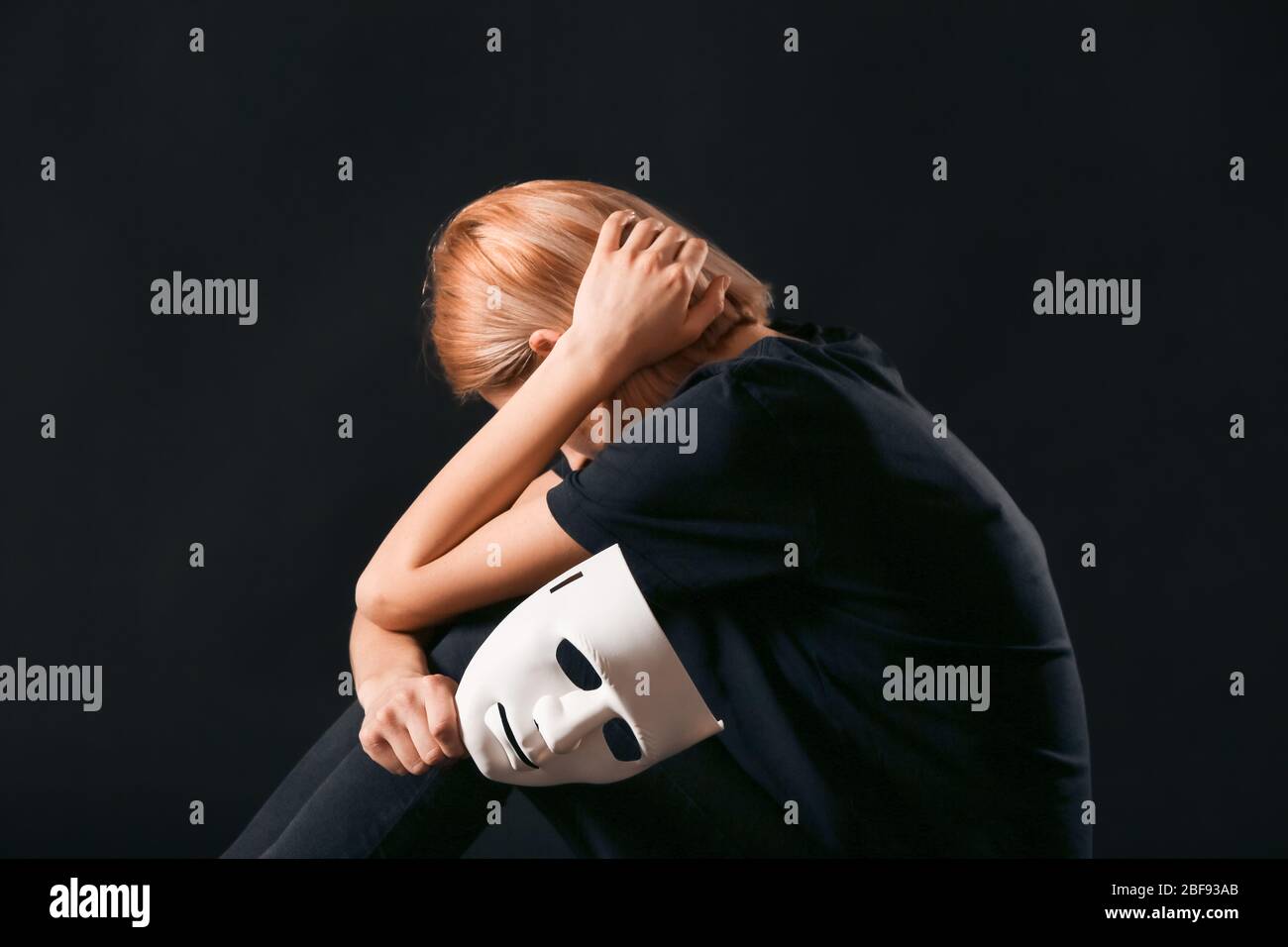 Woman holding mask on dark background. Concept of depression Stock ...