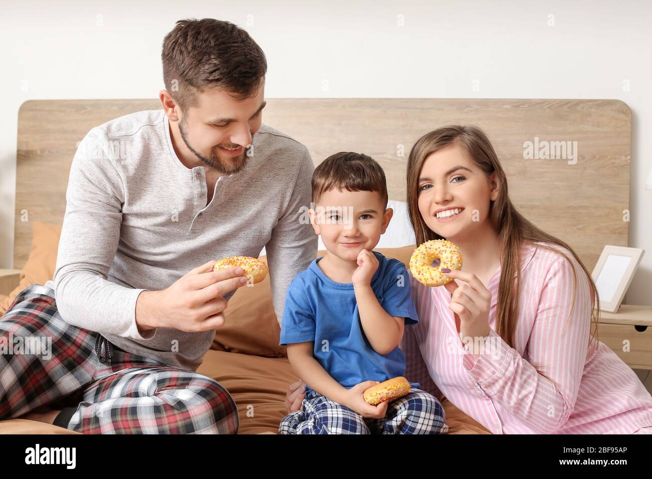 Happy family eating donuts in bedroom Stock Photo - Alamy