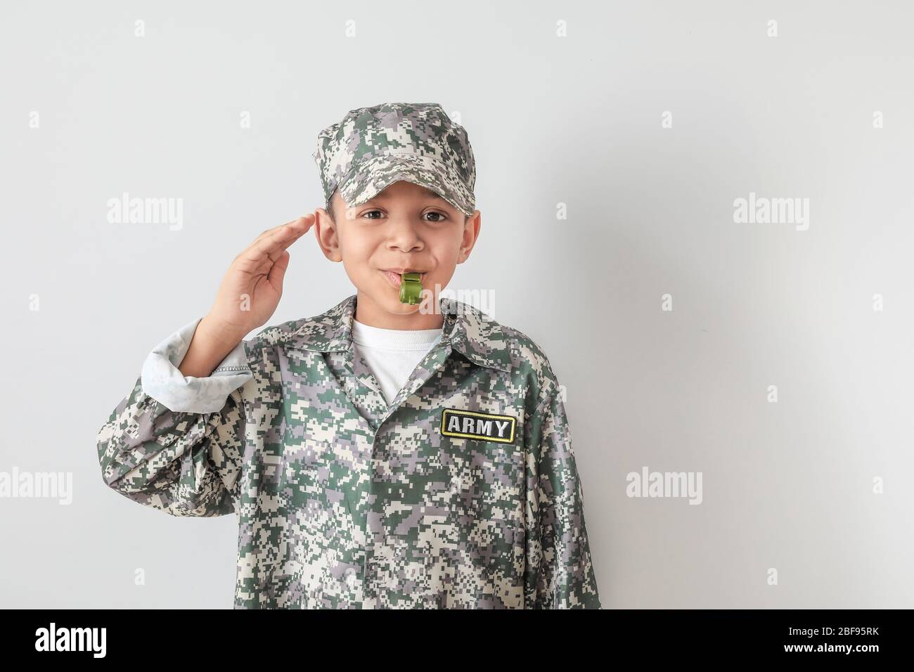 Little saluting African-American soldier with whistle on light ...
