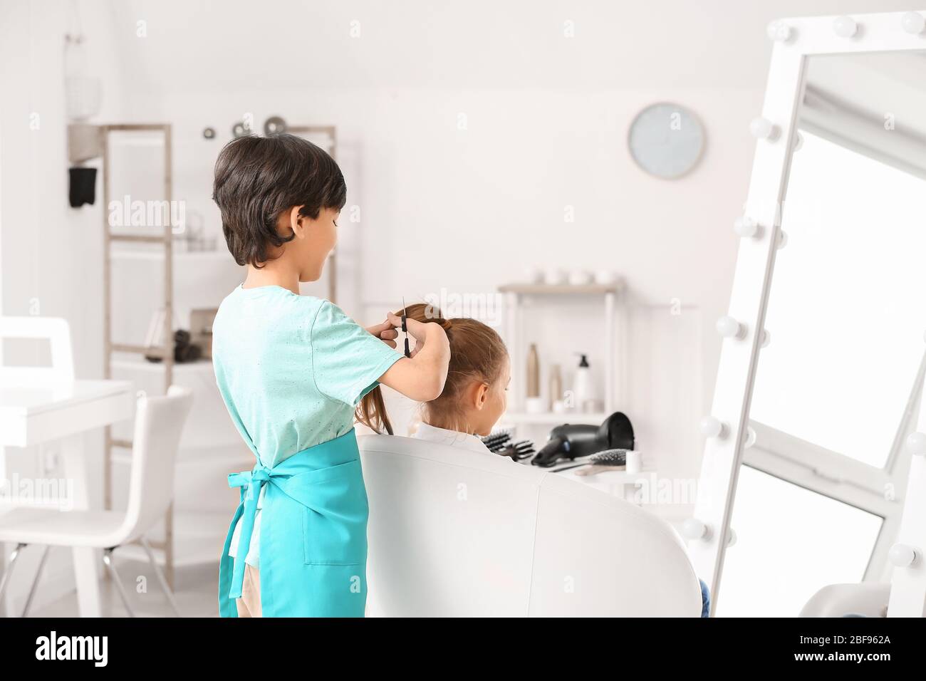 Cute little hairdresser working with client in salon Stock Photo - Alamy